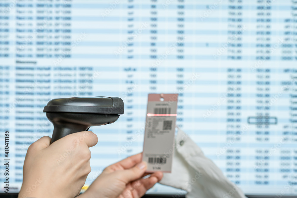 A warehouse woman employee accepts clothes using barcode scanner ...