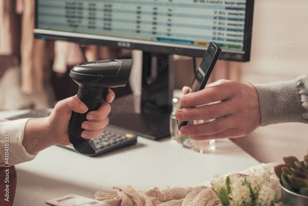 Woman cashier scanning qr code from buyer phone using barcode scanner ...