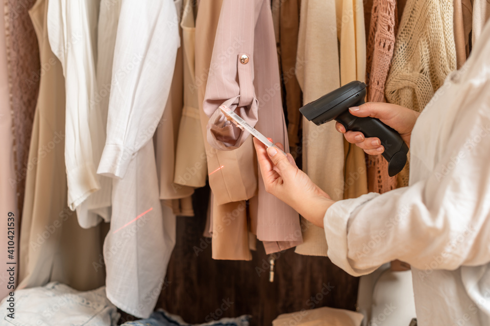 A warehouse woman employee accepts clothes using barcode scanner ...