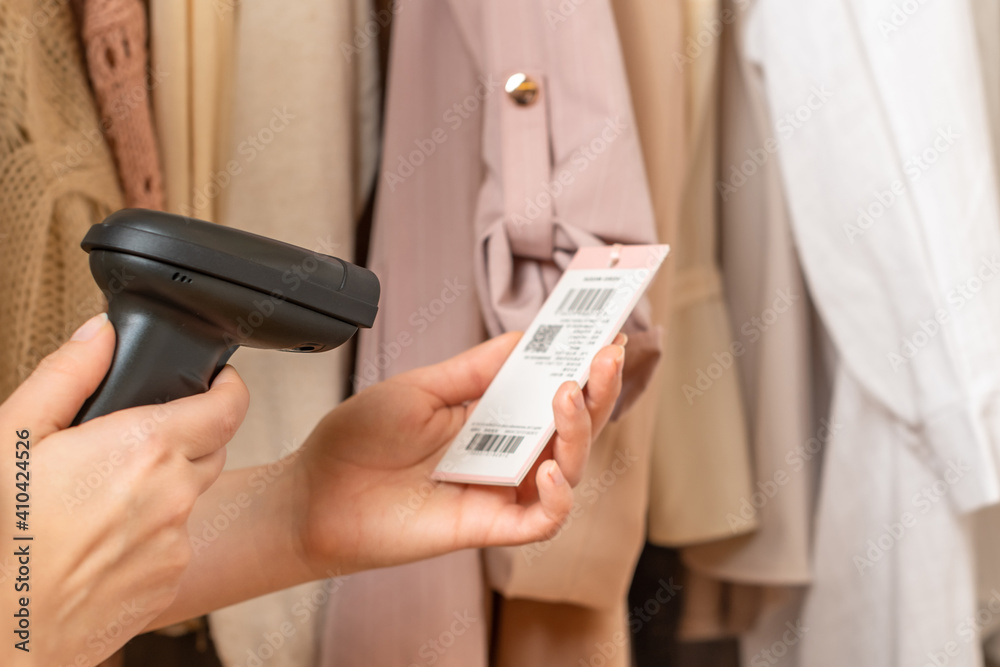 A warehouse woman employee accepts clothes using barcode scanner ...