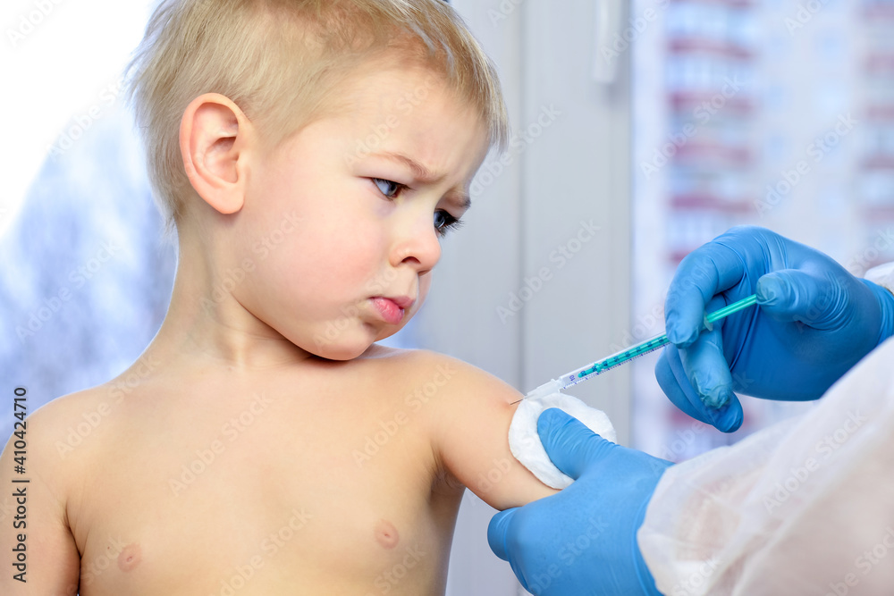 Doctor injecting vaccination in arm of a little boy. Coronavirus ...