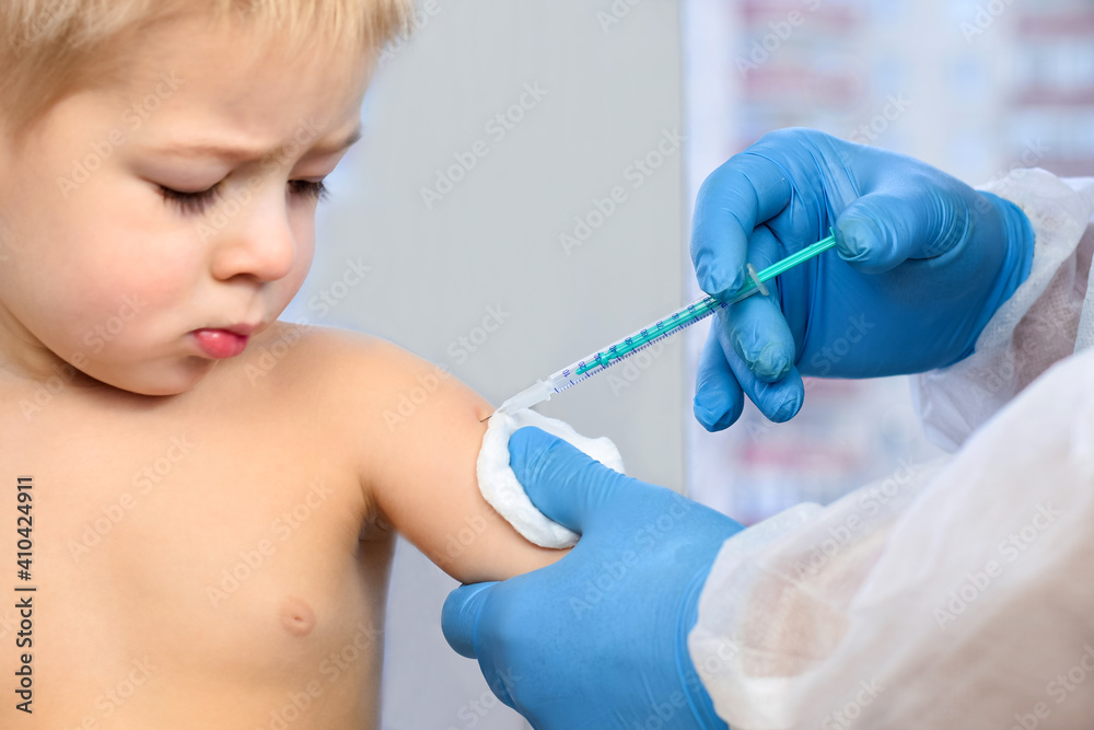 Doctor injecting vaccination in arm of a little boy. Coronavirus ...
