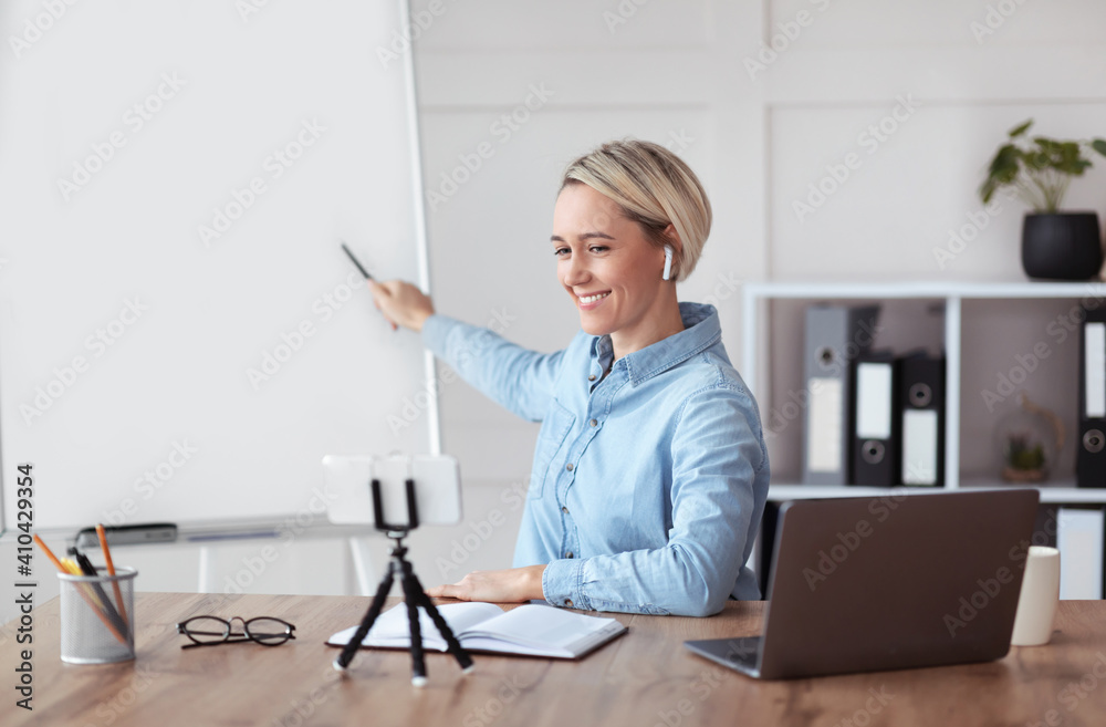 Joyful young teacher giving online private lesson from home, pointing ...