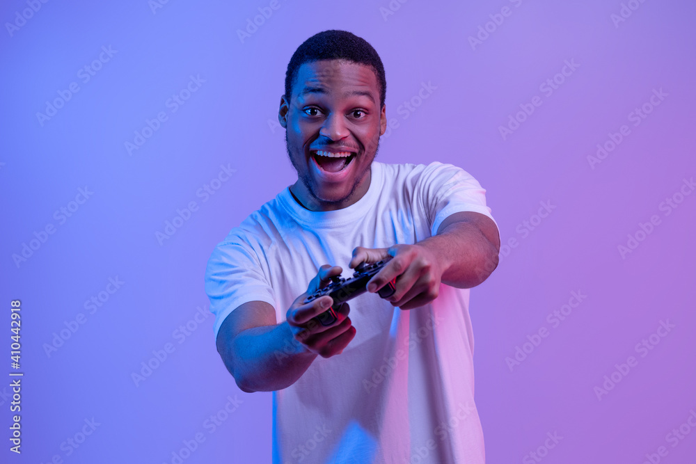 Overjoyed Black Gamer Man With Joystick Playing Video Games In Neon ...