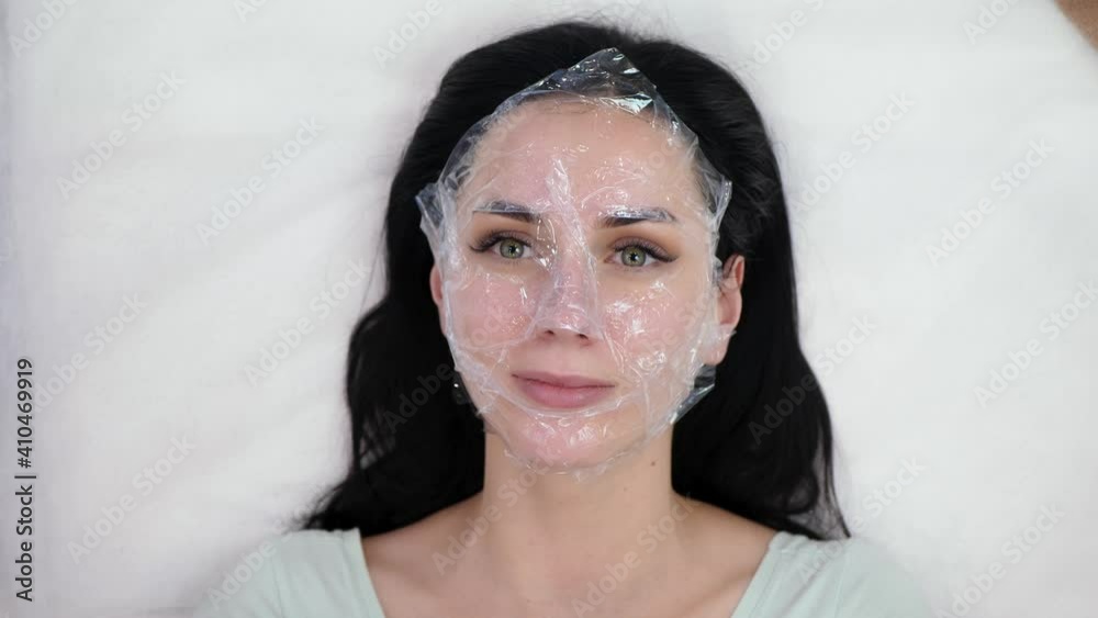 Beauty woman with plastic film on the face looking at camera, isolated ...
