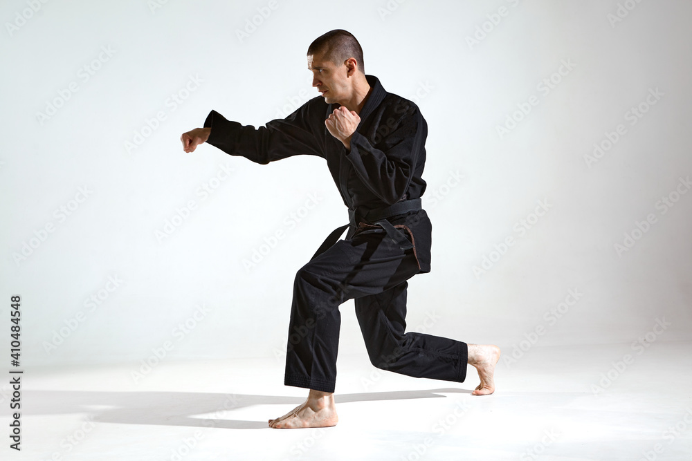 Athletic guy trainer in black kimono fighter showing karate technique ...