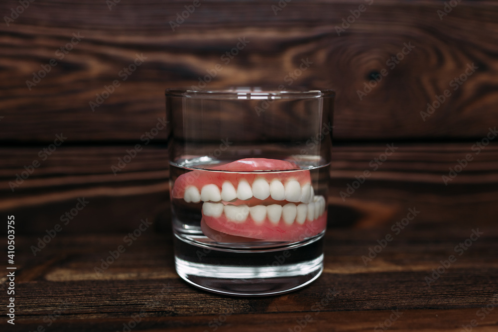 A denture in a glass of water. Dental prosthesis care. Full removable ...