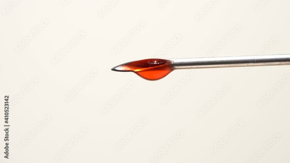 Drops of blood from the tip of the medical syringe. Bloody liquid ...