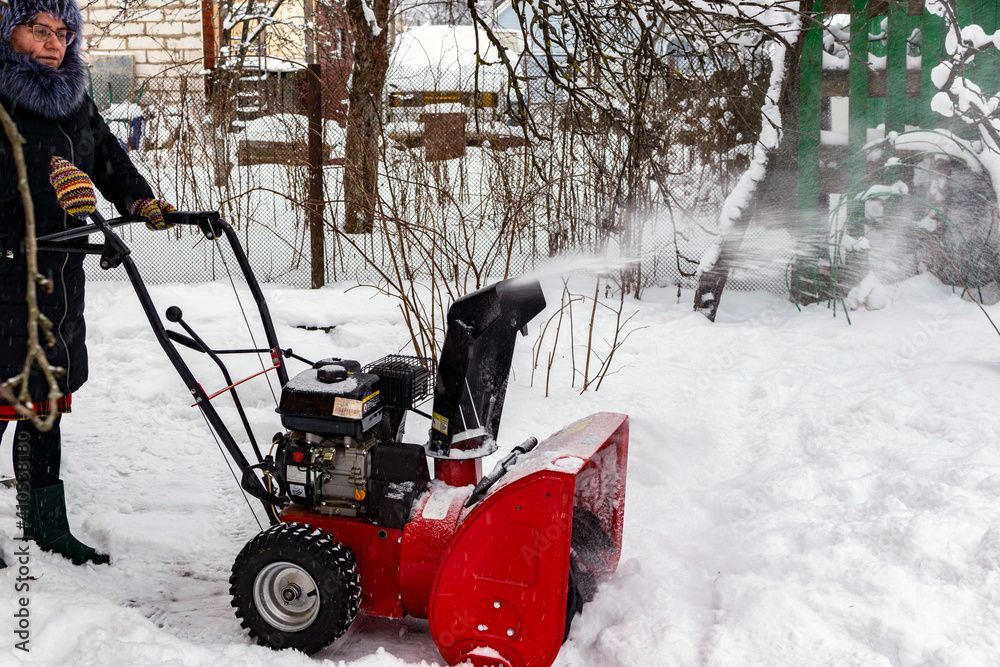 Cleans snow with a snowblower Stock Photo | Adobe Stock