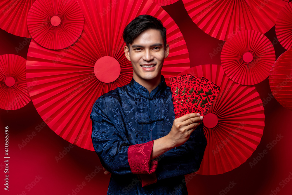 Handsome smiling Asian man in traditional costume holding red envelopes ...