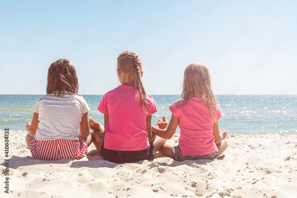 Back view three girls sitting on beach and looking at sea. Close-up ...