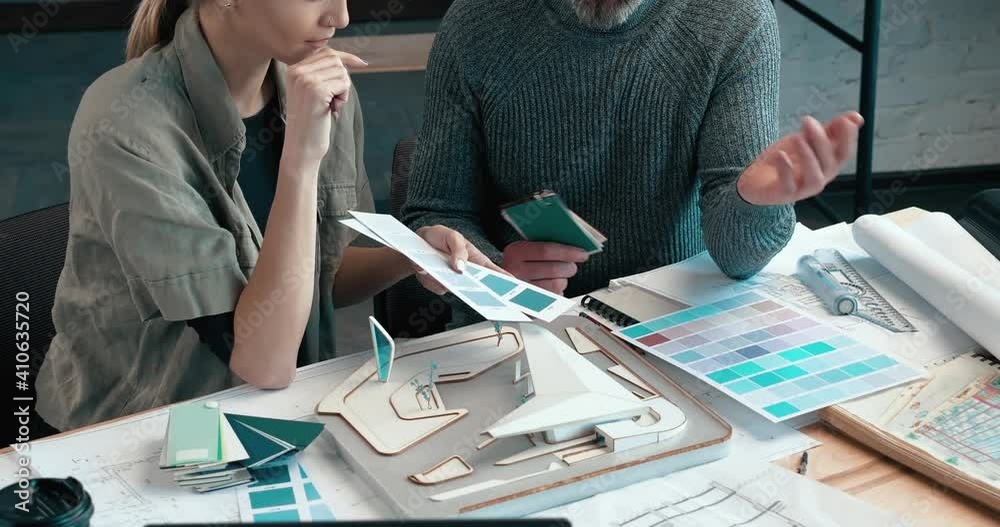 Woman and Man Design Experts with Model of Building talking in Office ...