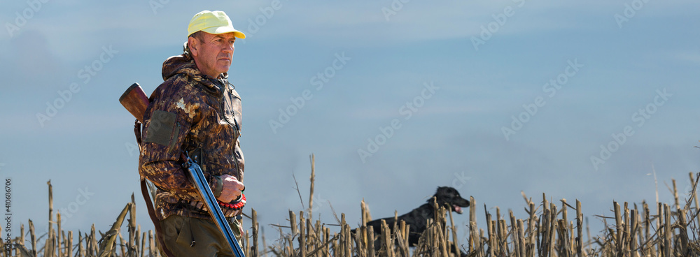 A hunter with a gun in his hands in hunting clothes in the autumn ...
