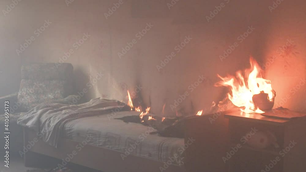 The bedroom is on fire with a lot of smoke. The bed, bedside table ...