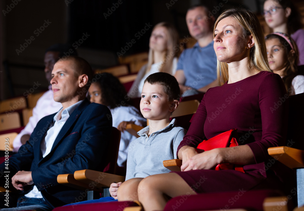 Young parents visiting theater with their tween son, consumed with ...