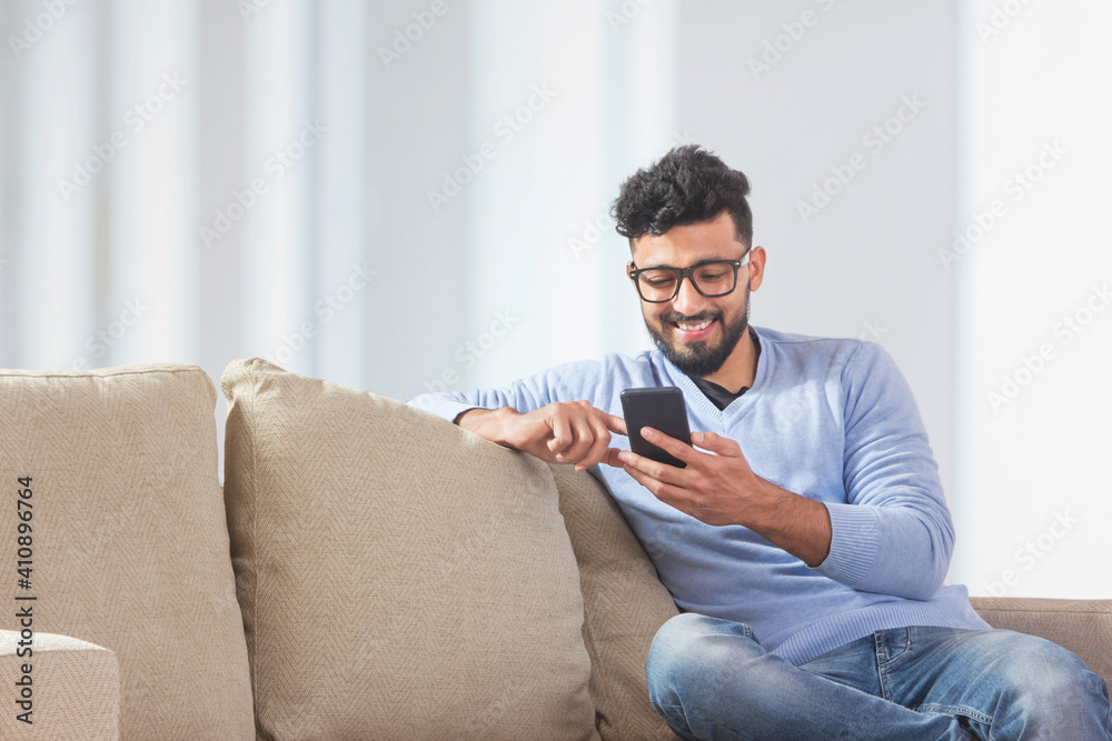 Young man sitting on the couch and using his mobile. Stock Photo ...