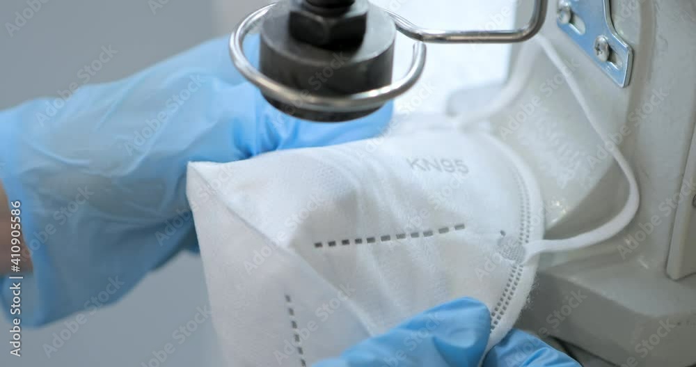 A worker in a protective suit connects a medical FFP3 mask. Hands ...