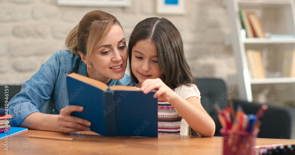 Little cute girl is studying and reading a book with her mother. Loving ...