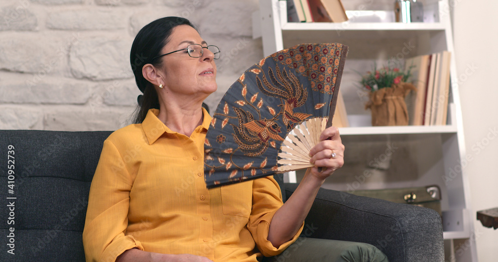 Beautiful old lady suffering from extreme heat in her home. The woman ...
