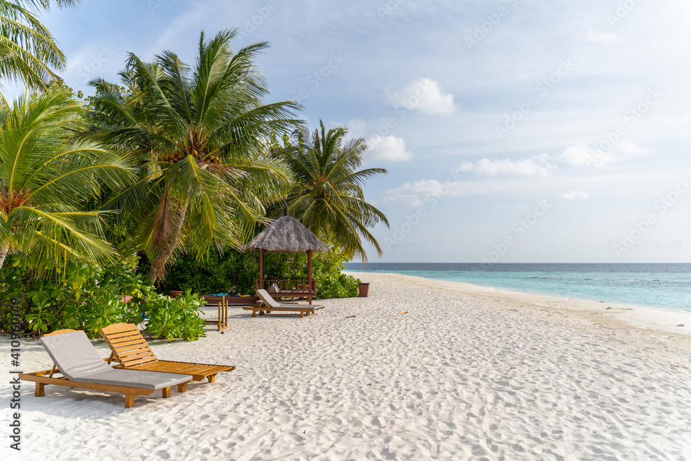 Traumhafter Strand mit Palmen und Sonnenliegen auf einer kleinen Insel ...