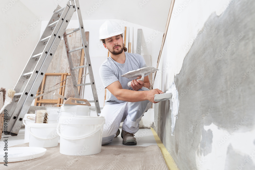 man plasterer construction worker at work, takes plaster from bucket ...