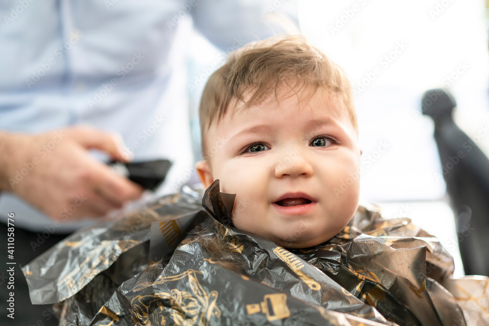 Portrait of cute small baby boy in barber shop getting his first ...