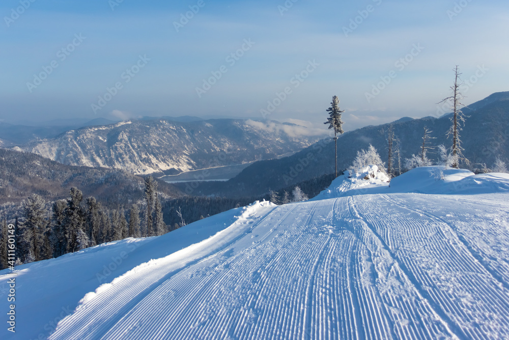 Tracks from the snowcat on the ski slope. View of the beautiful ...