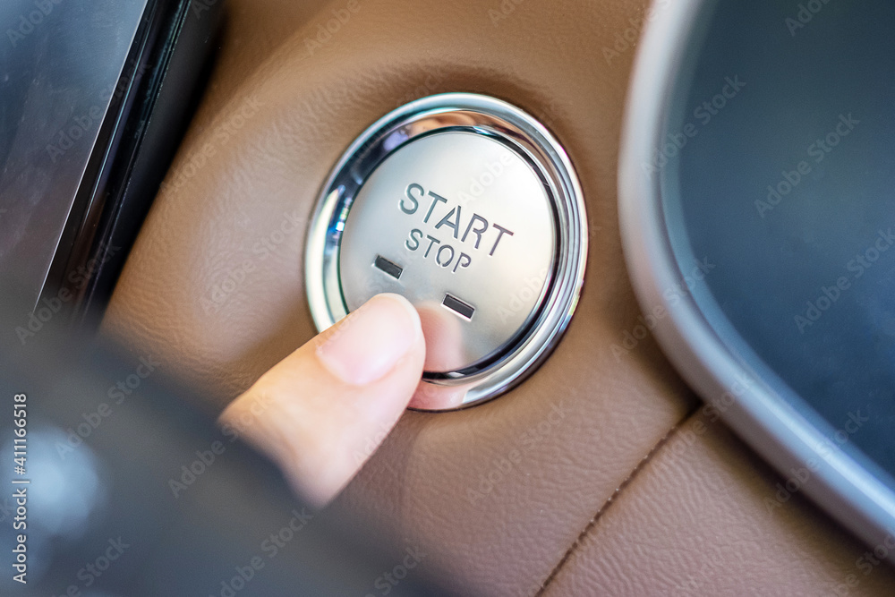 Finger press a car ignition button or START engine inside modern ...