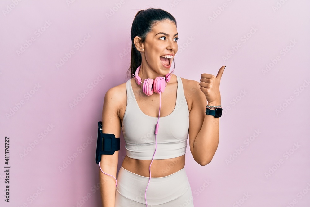 Young hispanic woman wearing gym clothes and using headphones smiling ...