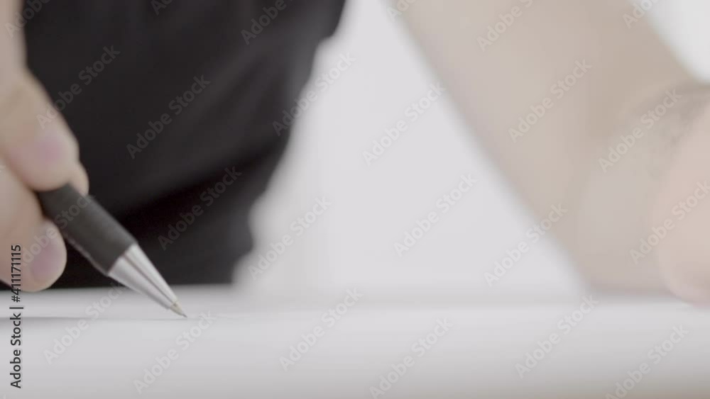 Close-up shot of a hand seen scribbling something on a large sheet of ...