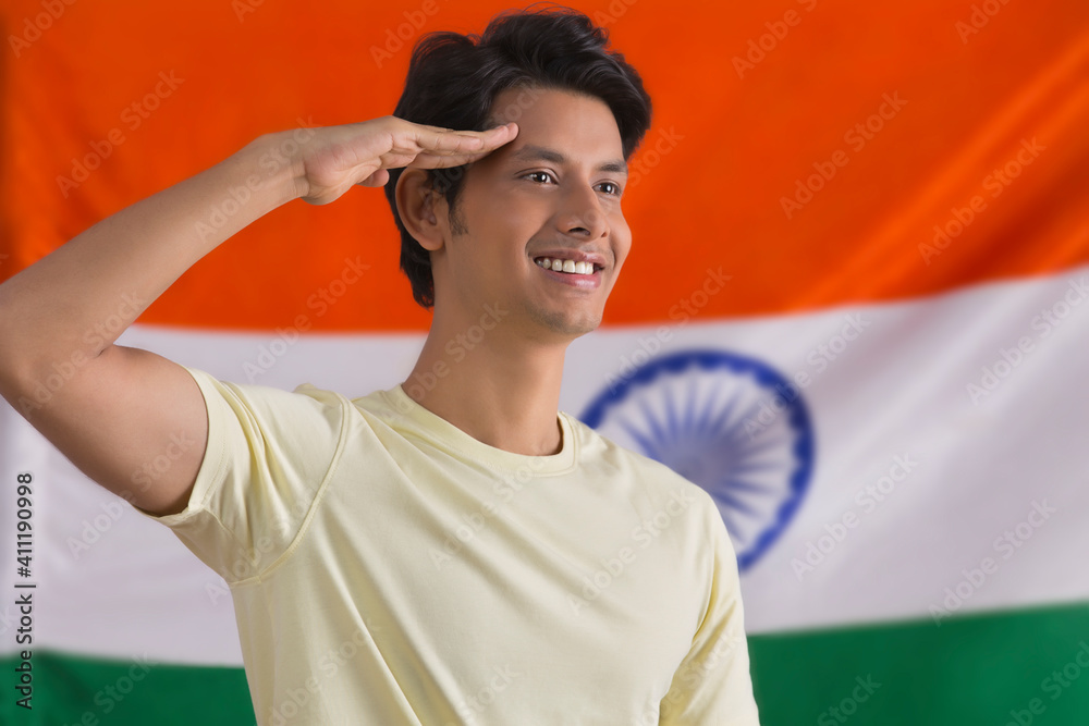 young man saluting while standing in front of indian flag, independence ...