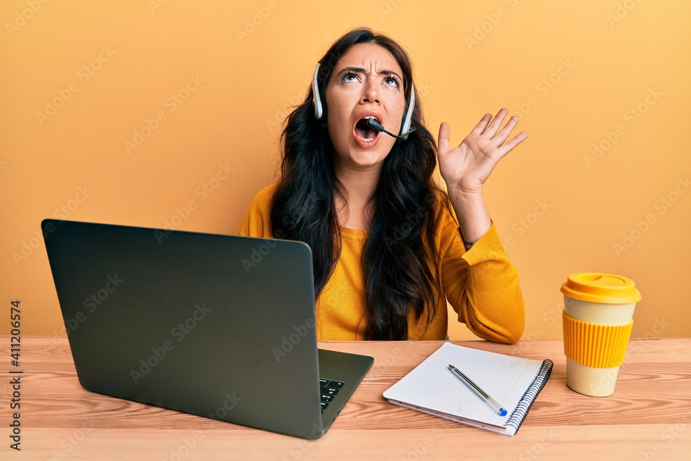 Beautiful brunette young woman wearing call center agent headset angry ...