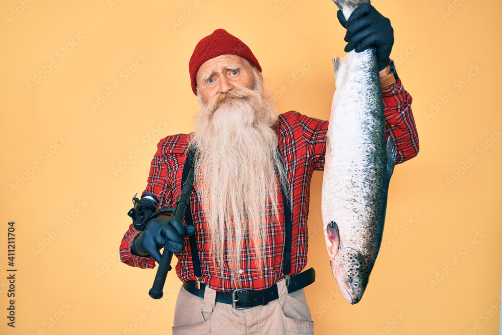 Old senior man with grey hair and long beard holding fishing rod and ...