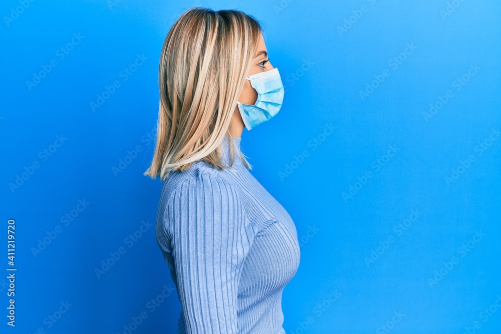 Beautiful blonde woman wearing covid-19 medical mask looking to side ...