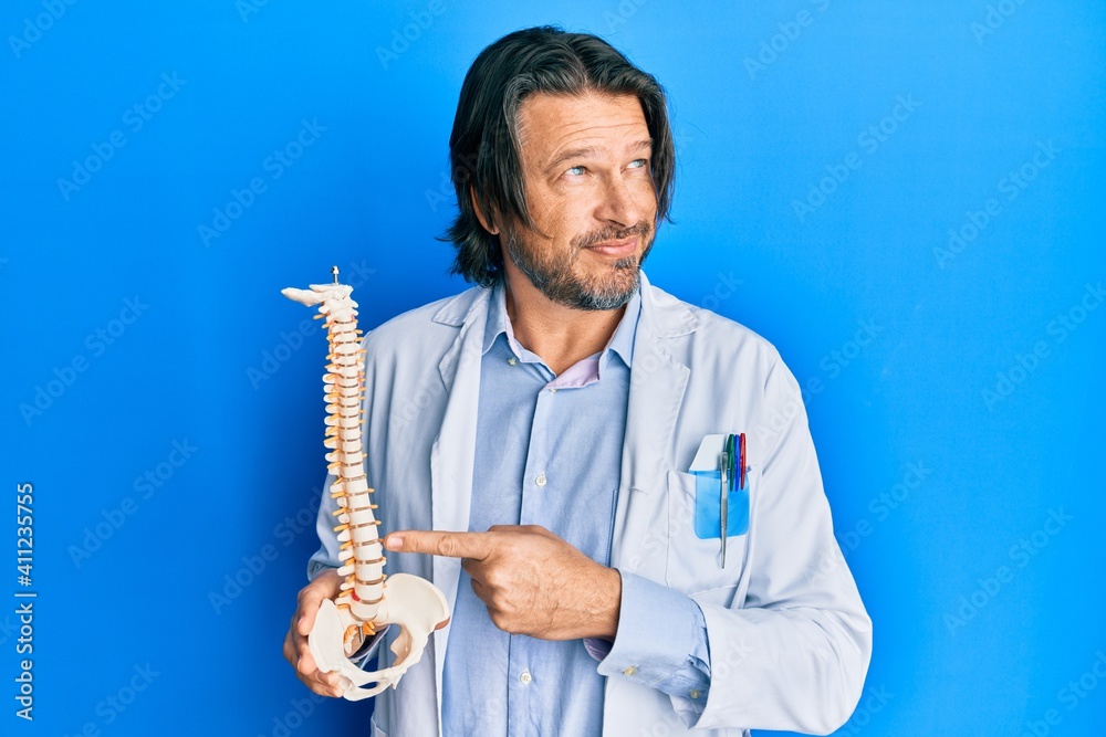 Middle age handsome traumatologist man holding anatomical model of ...