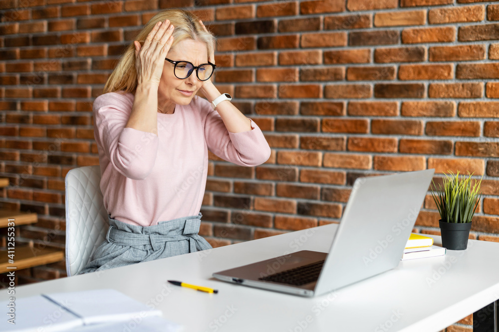 Bewildered middle aged business woman wearing stylish eyeglasses and ...