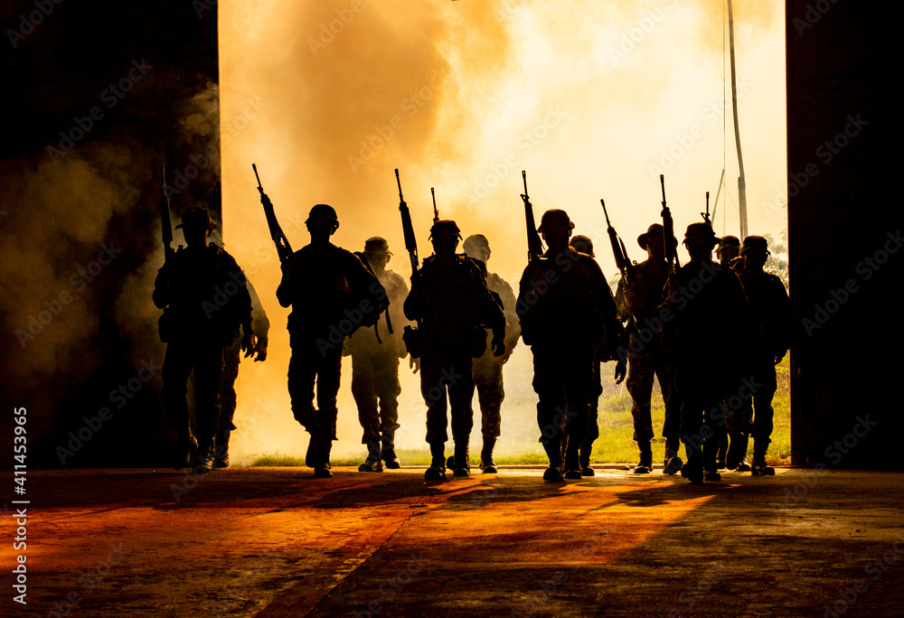 Silhouettes of army soldiers in the fog against a sunset, marines team ...