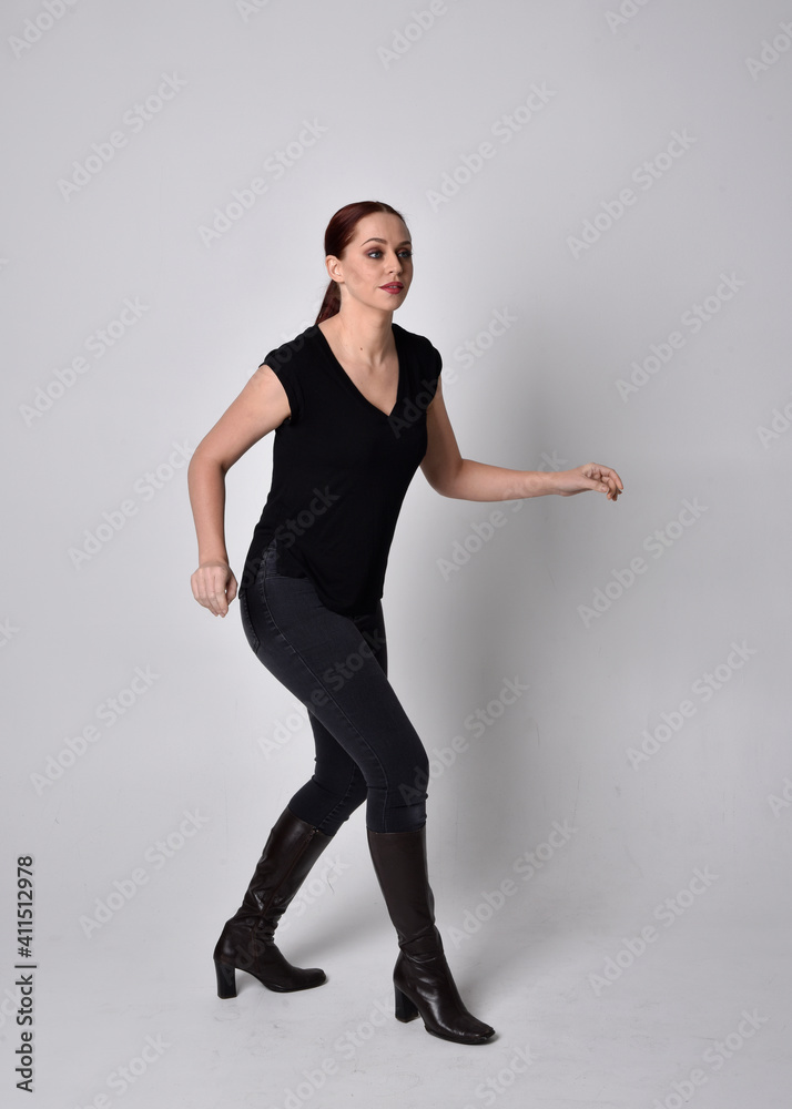 Simple full length portrait of woman with red hair in a ponytail ...