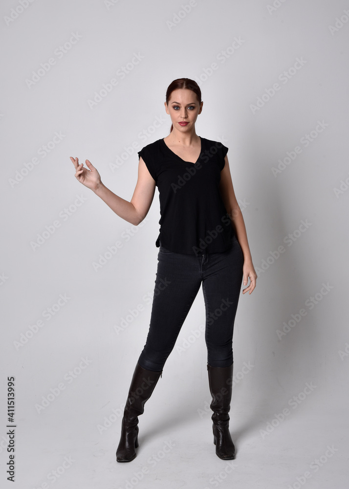 Simple full length portrait of woman with red hair in a ponytail ...
