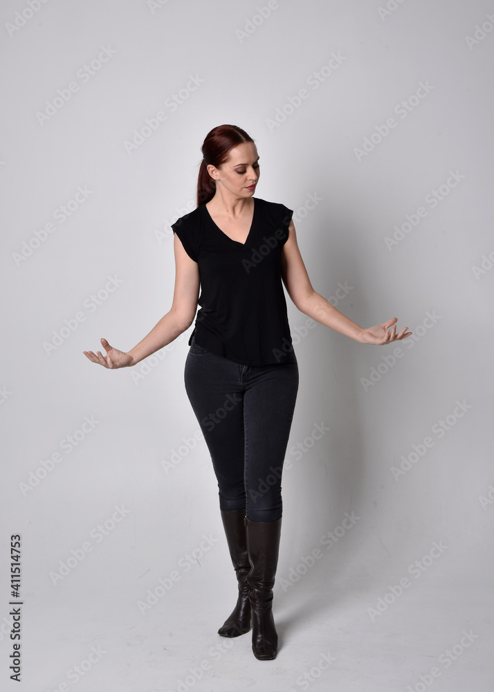 Simple full length portrait of woman with red hair in a ponytail ...