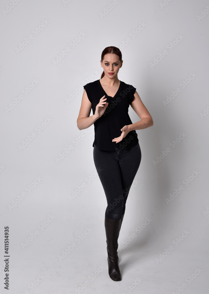 Simple full length portrait of woman with red hair in a ponytail ...