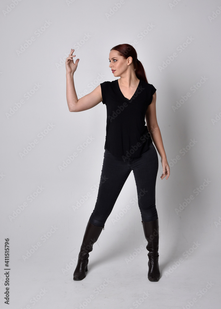 Simple full length portrait of woman with red hair in a ponytail ...