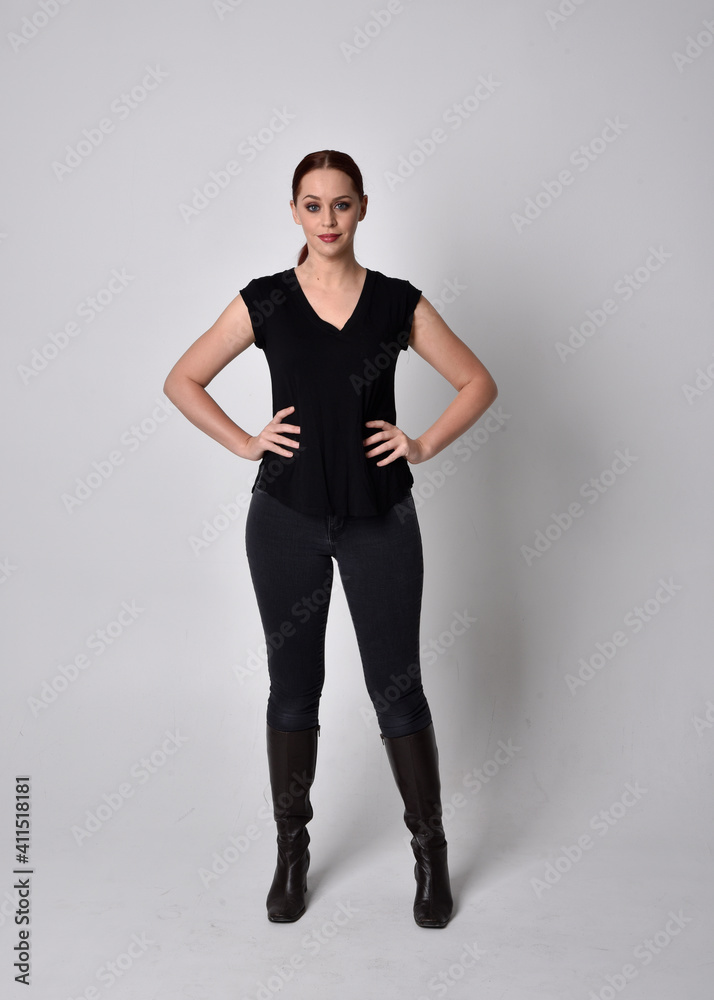 Simple full length portrait of woman with red hair in a ponytail ...