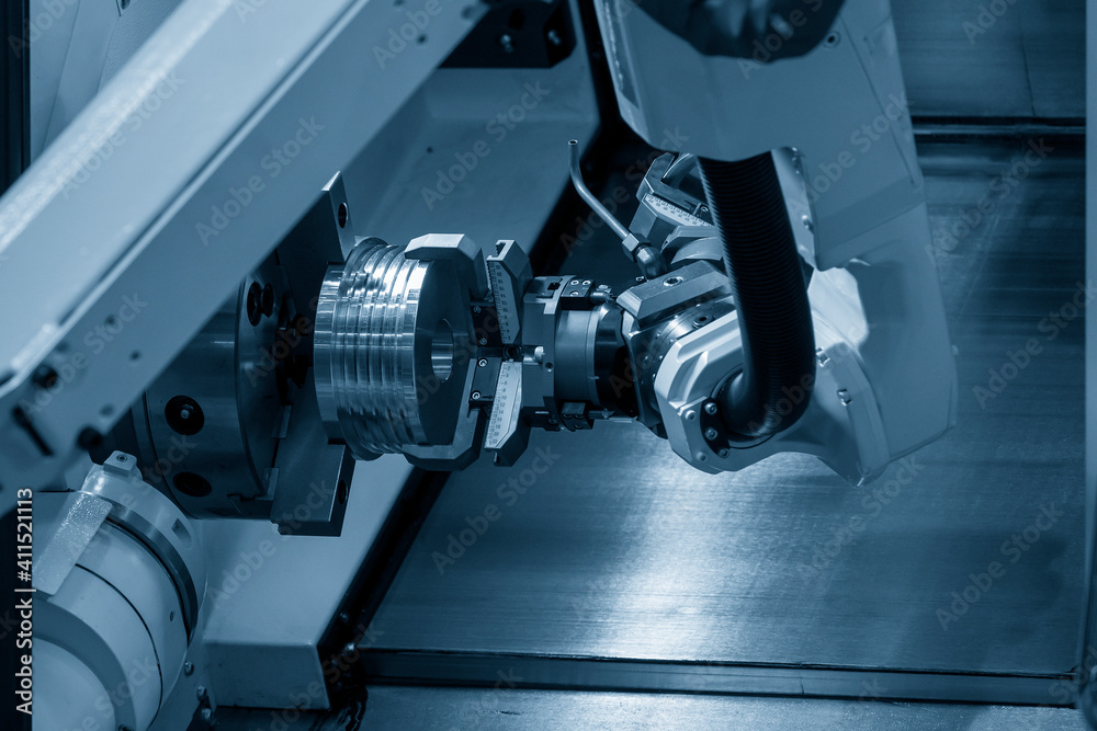 The robotics arm gripping the metal part from CNC lathe machine with ...