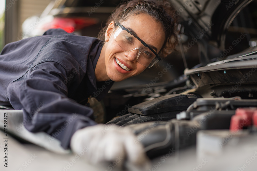 Foto de Female mechanic smiling and working repair maintenance a car in ...