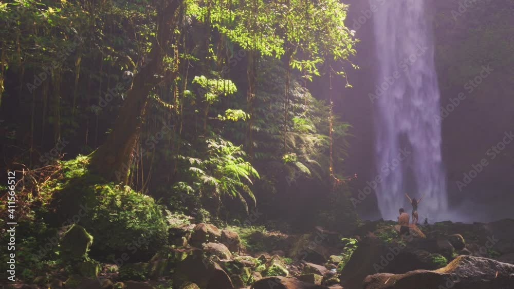 Silhouette couple in love enjoying beautiful waterfall in the rays of ...