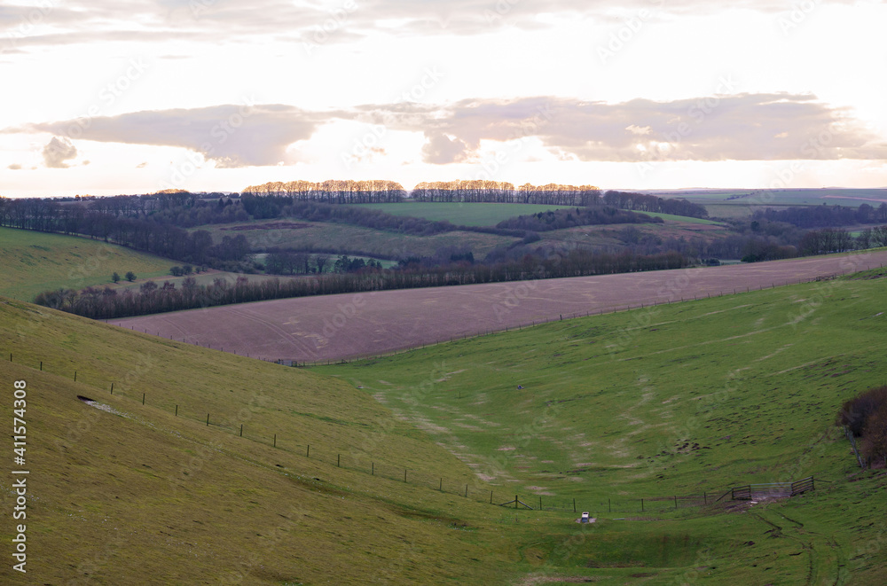 looking down a long English valley with fields green grass, red soil ...