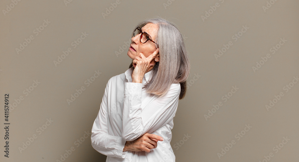senior woman with a concentrated look, wondering with a doubtful ...