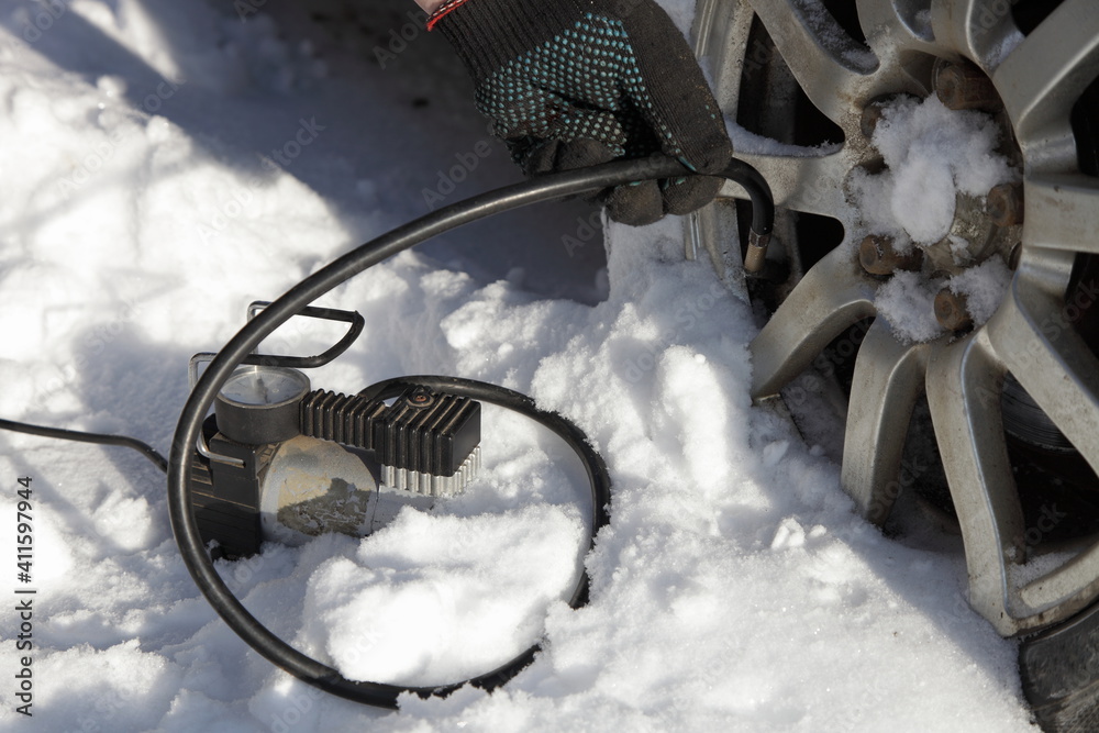 Car tire inflation with compact electric air tire compressor on white ...