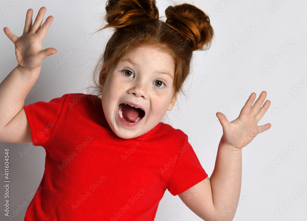 Child screams loudly. Stylish little girl with freckles and red hair ...